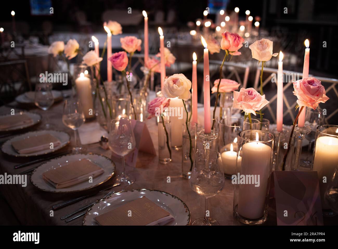Chivalric wedding with pillars of candles and roses in glass vases ...