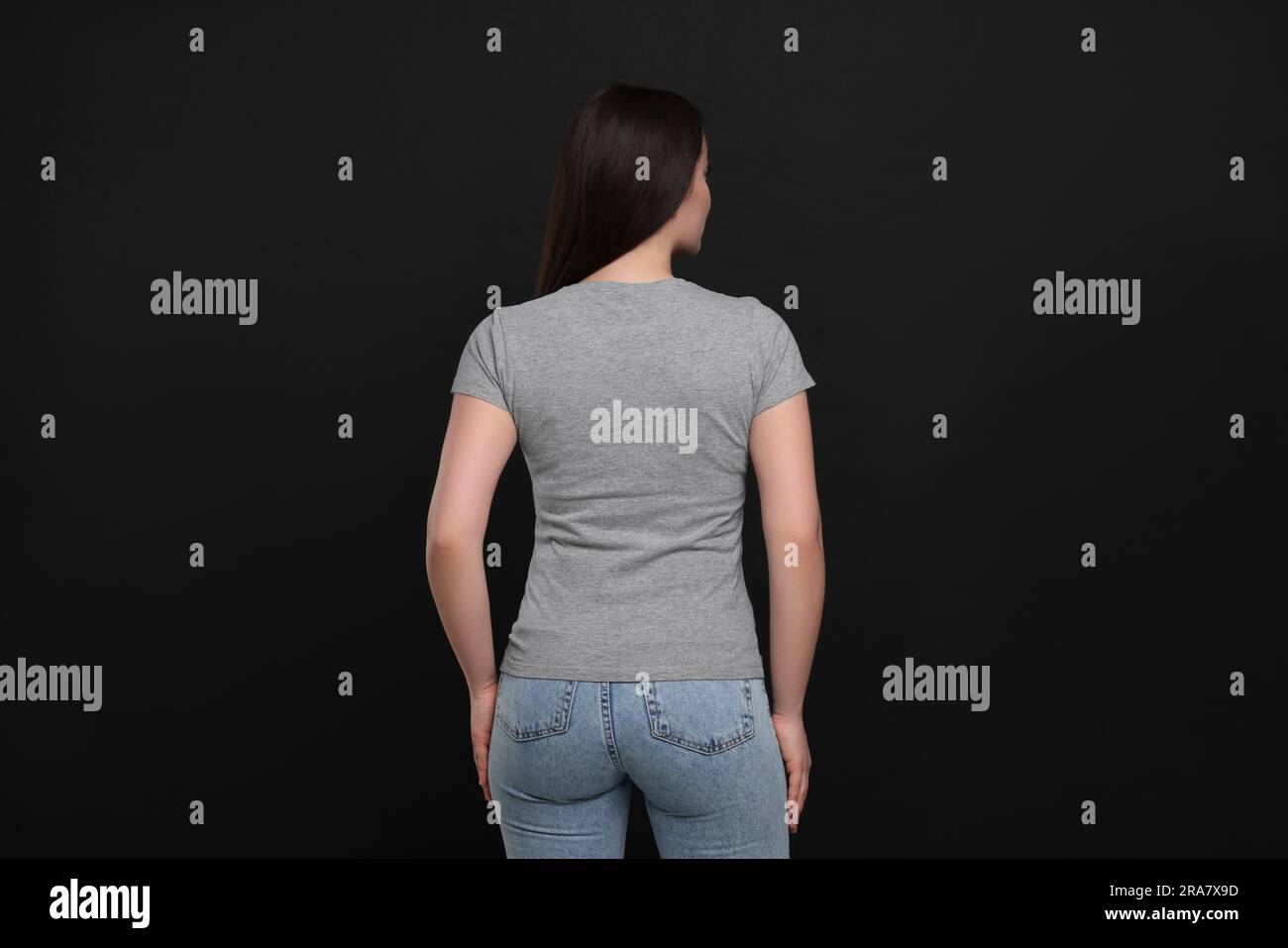 Woman wearing grey t-shirt on black background, back view Stock Photo ...