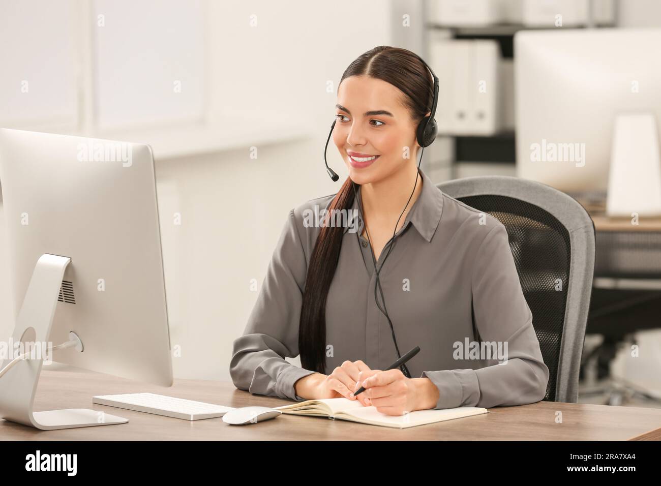 Hotline operator with headset and notebook working in office Stock ...