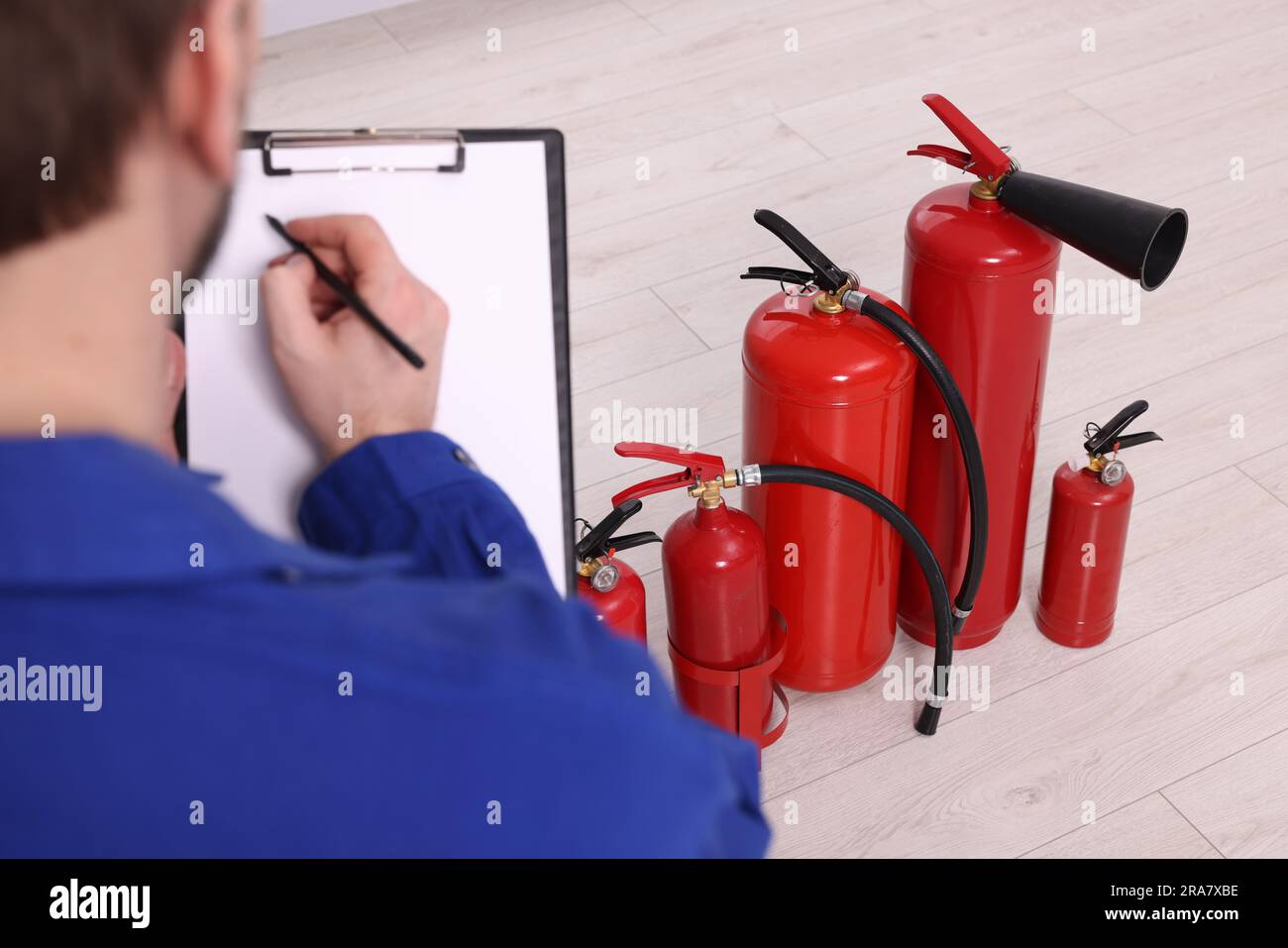 Man with clipboard checking fire extinguishers indoors, closeup Stock ...