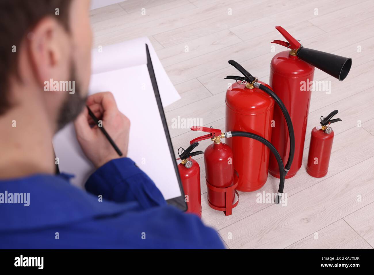 Man with clipboard checking fire extinguishers indoors, closeup Stock ...
