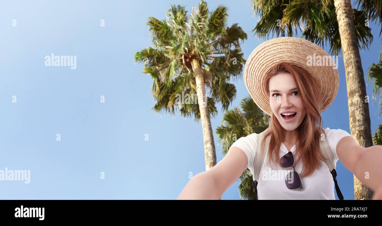 Beautiful woman in straw hat taking selfie near tropical palms. Banner ...