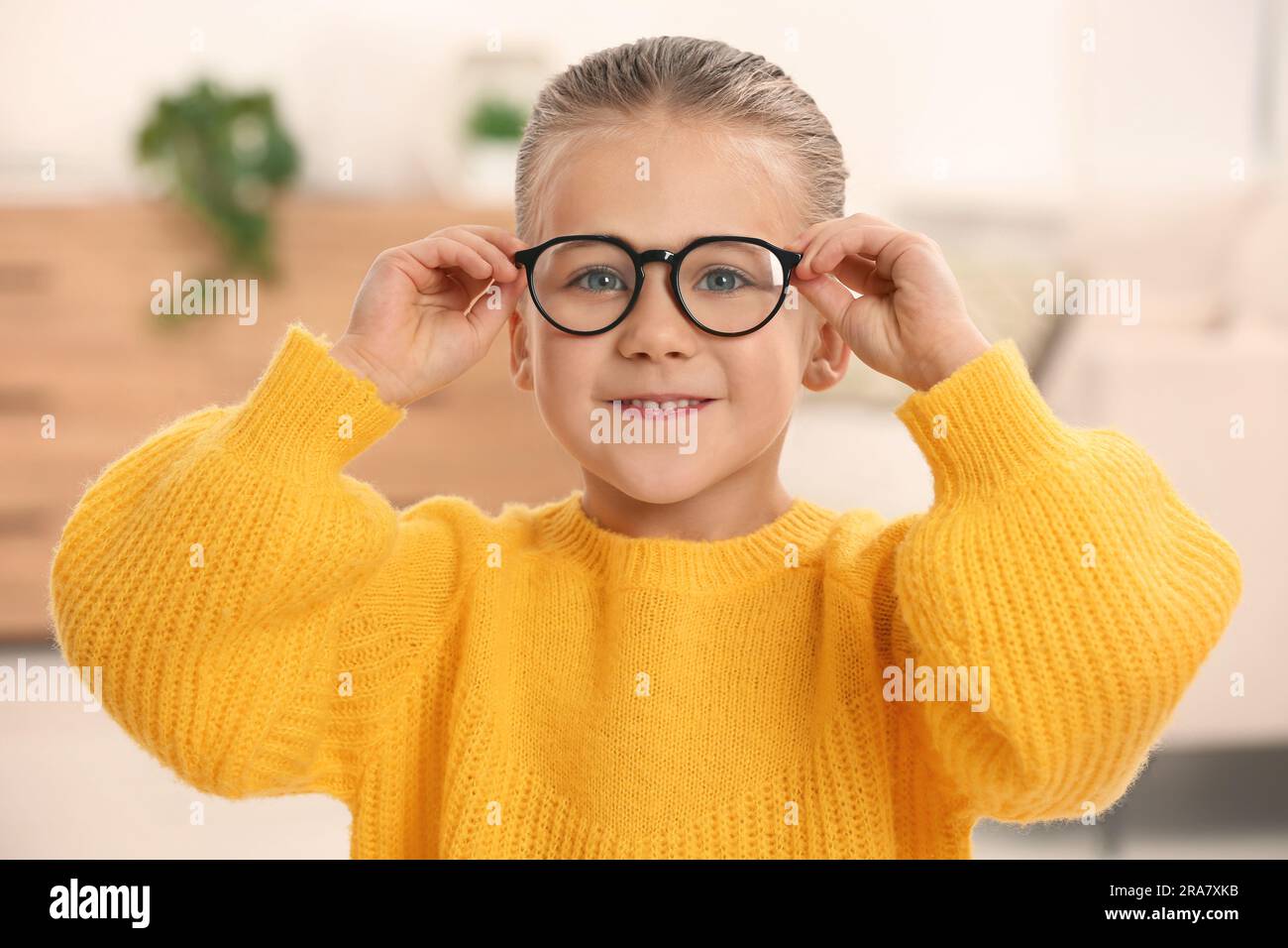 Portrait of cute little girl wearing glasses indoors Stock Photo - Alamy