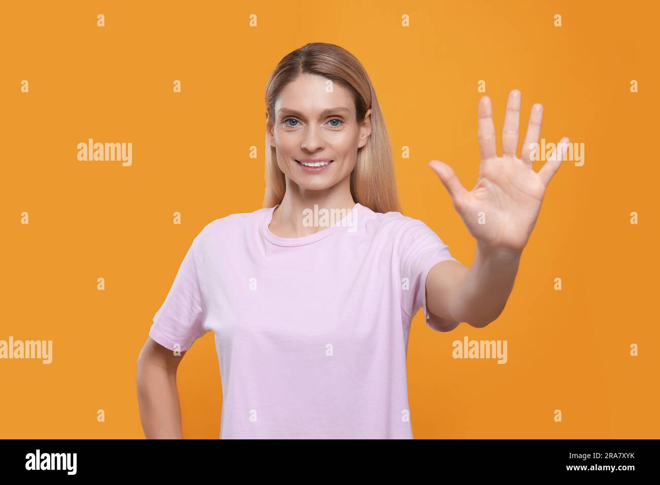 Woman giving high five on orange background Stock Photo - Alamy