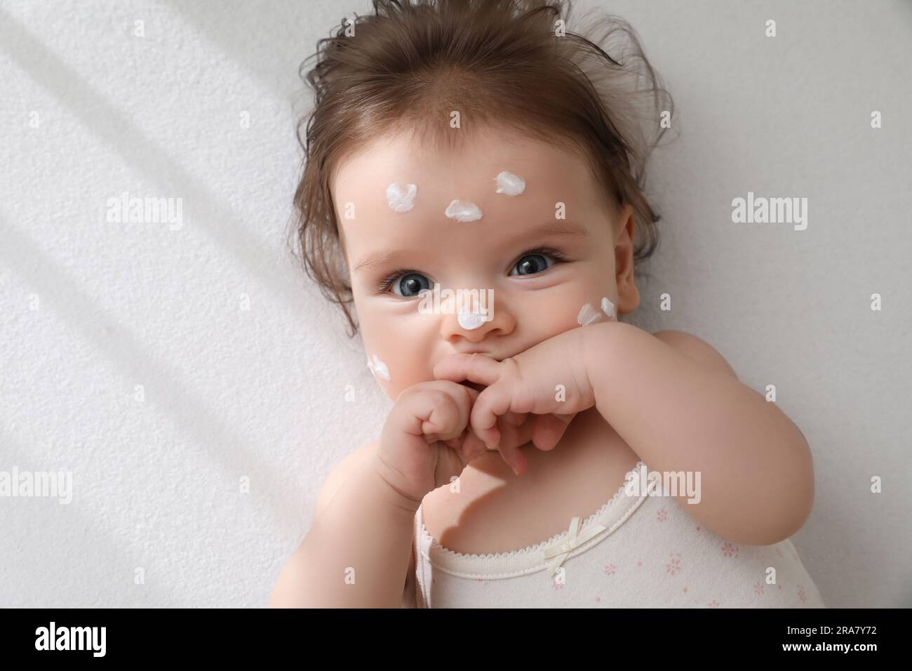 Cute little baby with cream on face in comfortable crib, top view ...