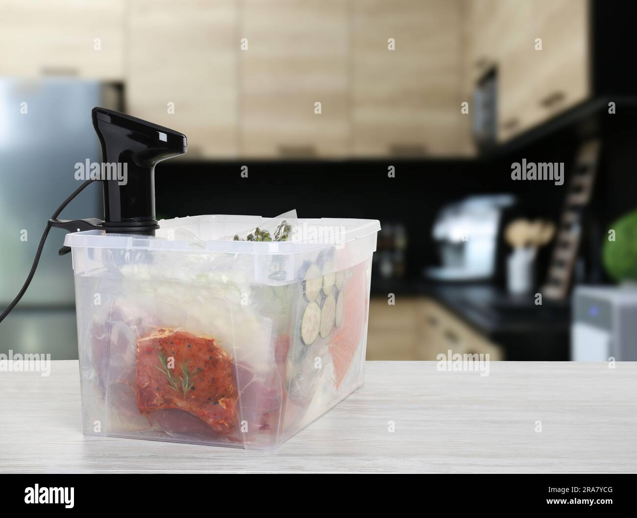 Sous vide cooker and vacuum packed food products in box on wooden table ...