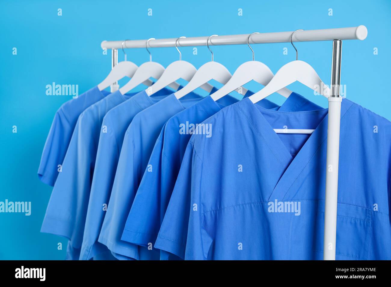 Medical uniforms on rack against light blue background Stock Photo - Alamy