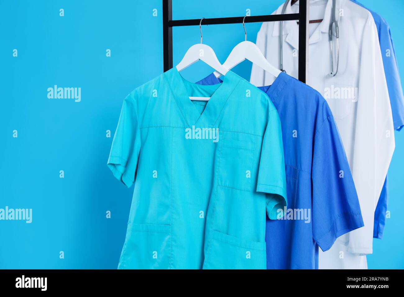 Medical uniforms on metal rack against light blue background Stock ...
