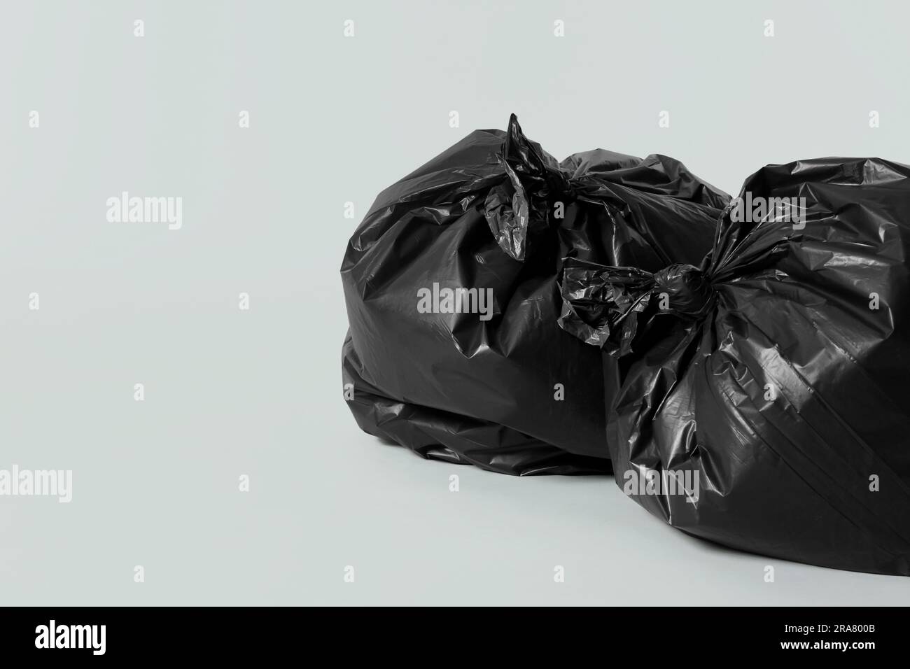 Trash bags full of garbage on light grey background. Space for text ...