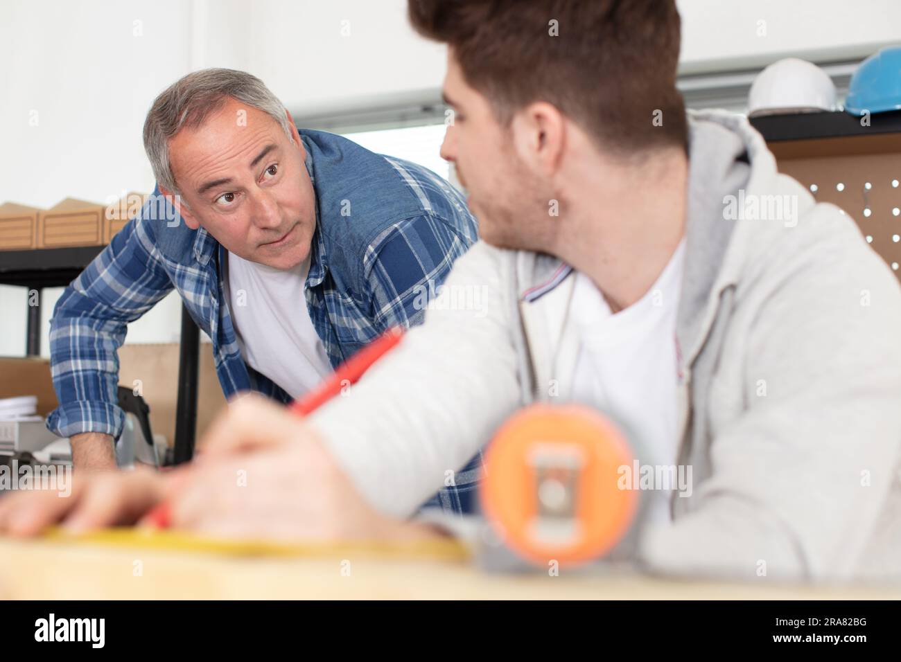 carpenter showing apprentice how to use sawing machine Stock Photo - Alamy