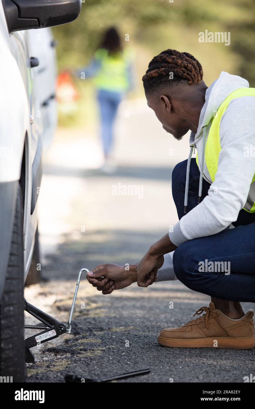 young guy lifting the car for changing wheel Stock Photo - Alamy