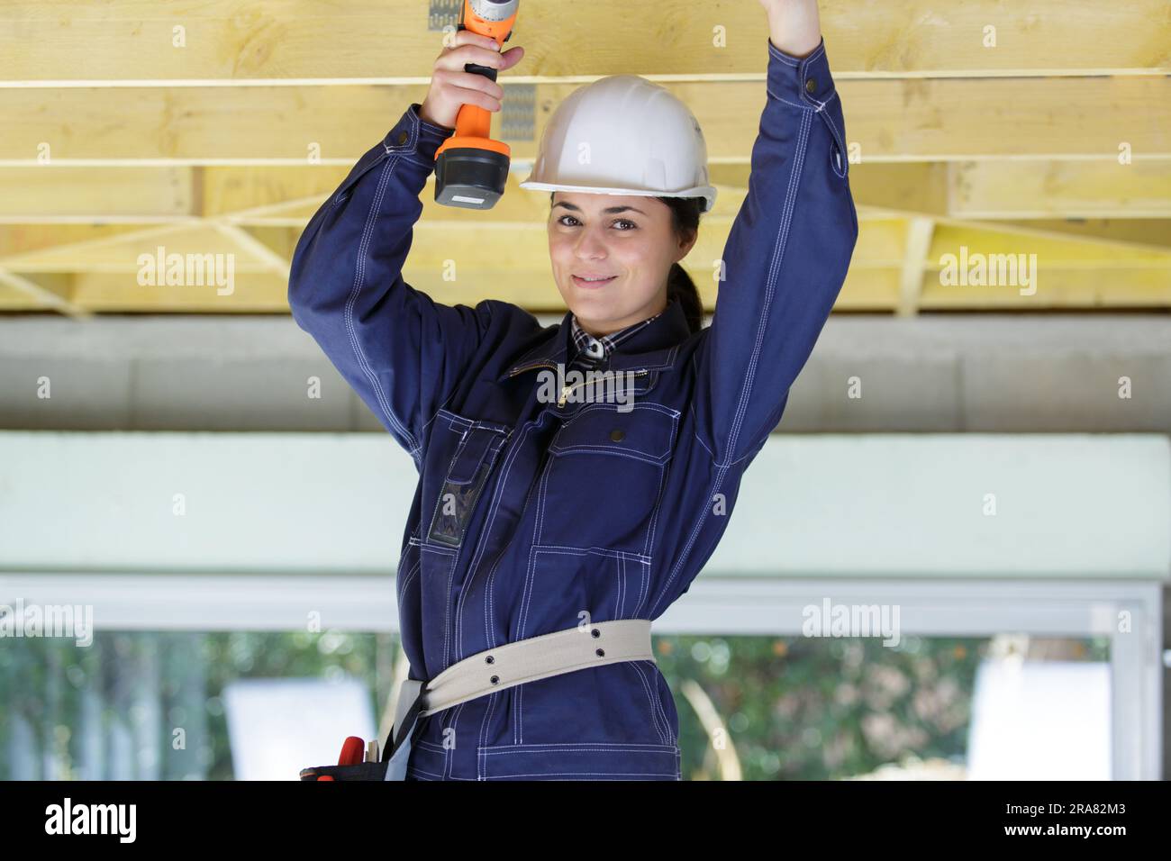 female contractor using a cordless drill on roof timbers Stock Photo ...
