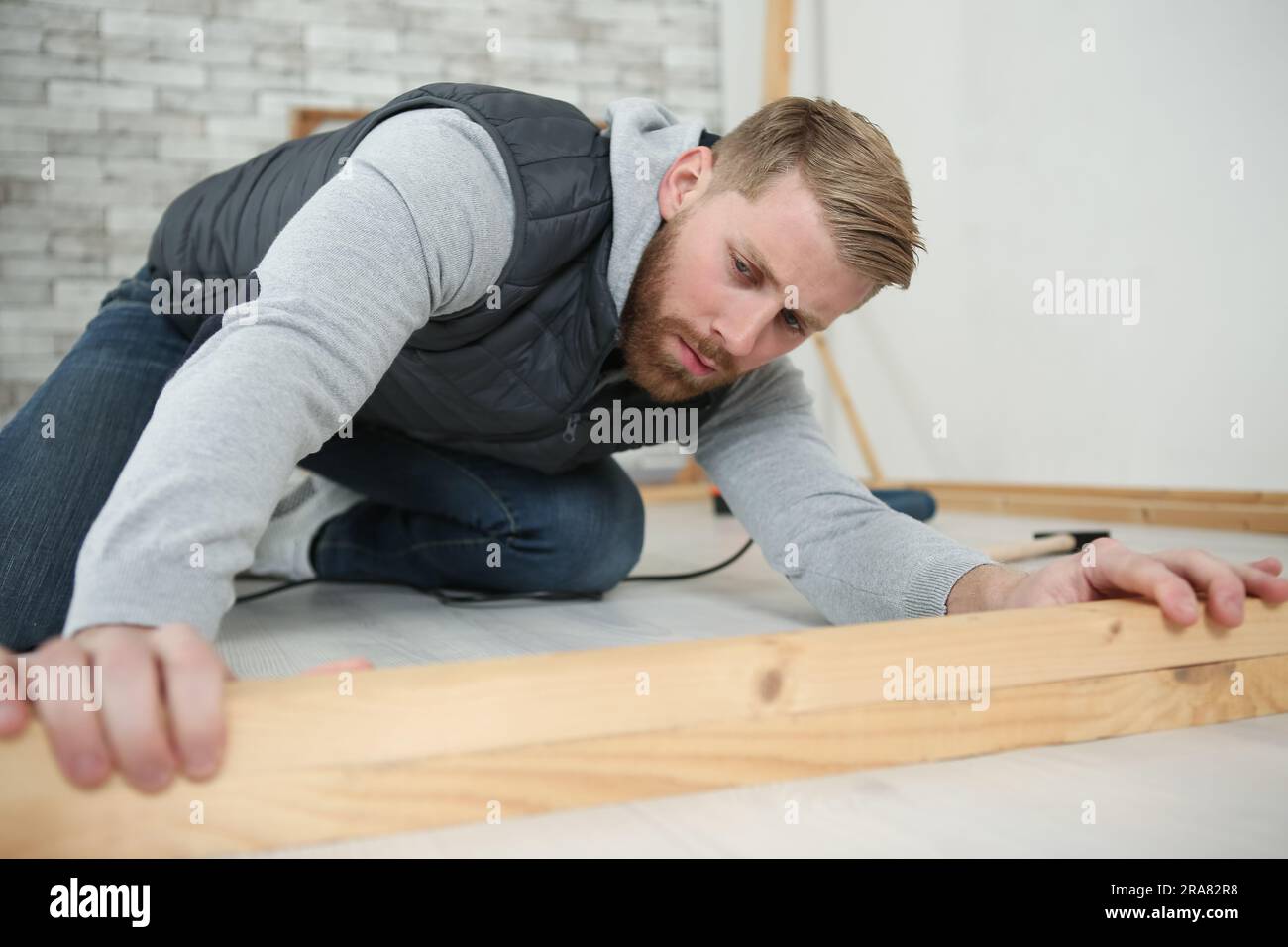 man is engaged in laying laminate wood floor Stock Photo - Alamy
