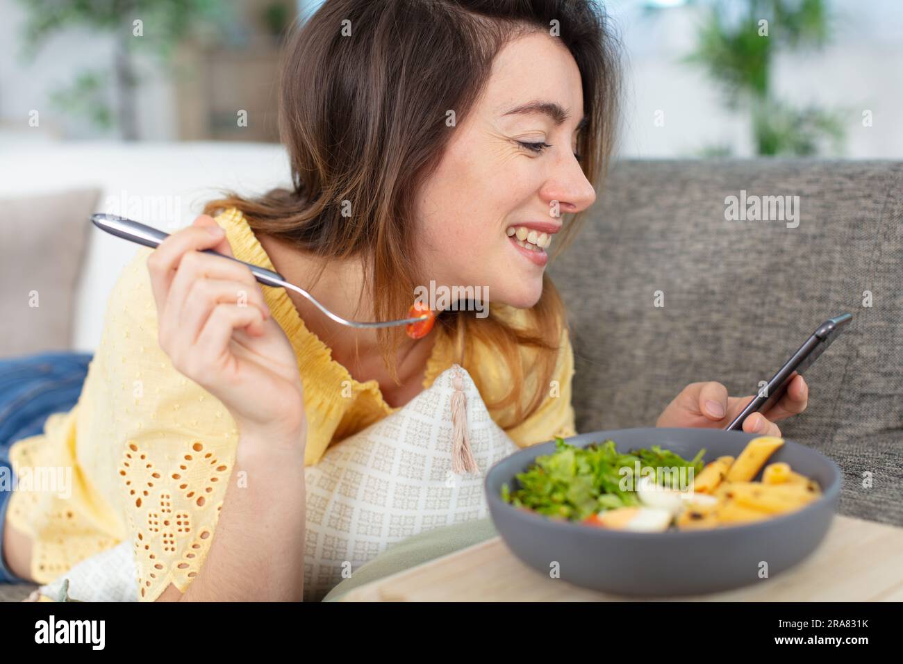 woman sitting on the couch ready to eat Stock Photo - Alamy