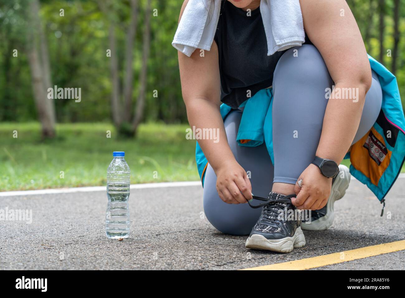 Young overweight woman stops to tie her shoe during her morning ...