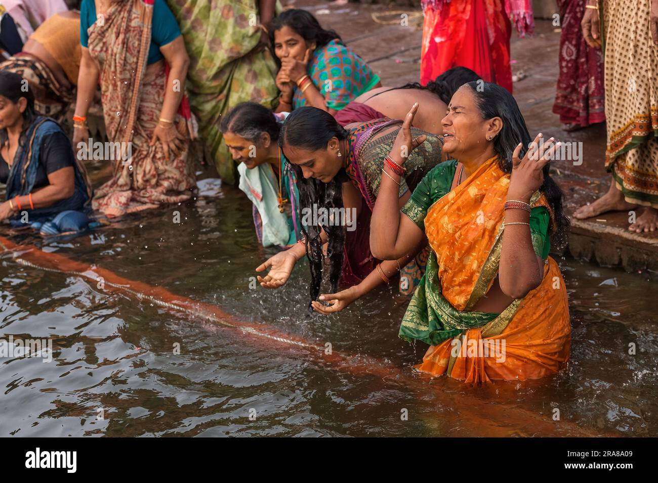 Women perform ritual bathing in the waters of the sacred Ganges River ...