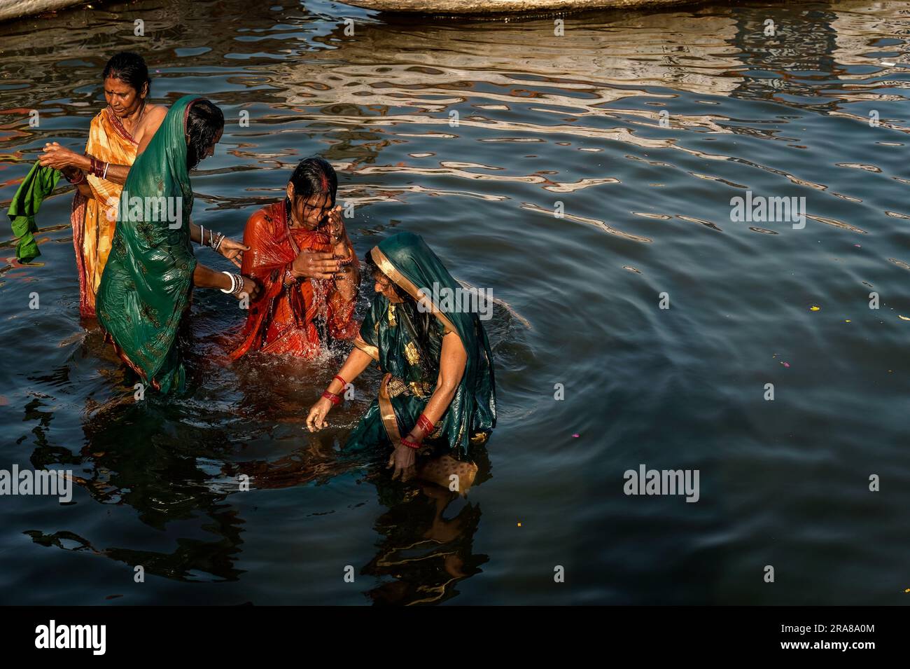 Women perform ritual bathing in the waters of the sacred Ganges River ...