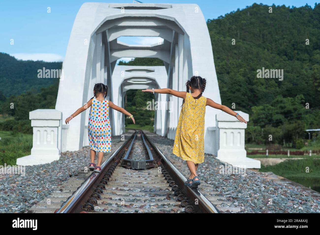 Children playing outside on train tracks. Asian sisters walking on the ...
