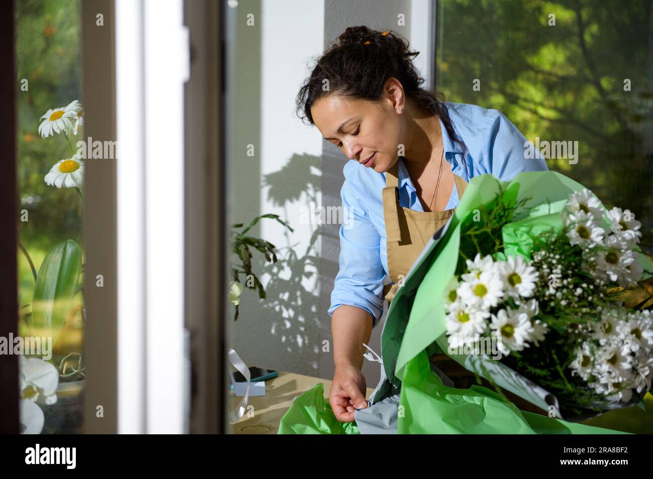 Female florist, event manager arranging a bouquet of flowers in a ...