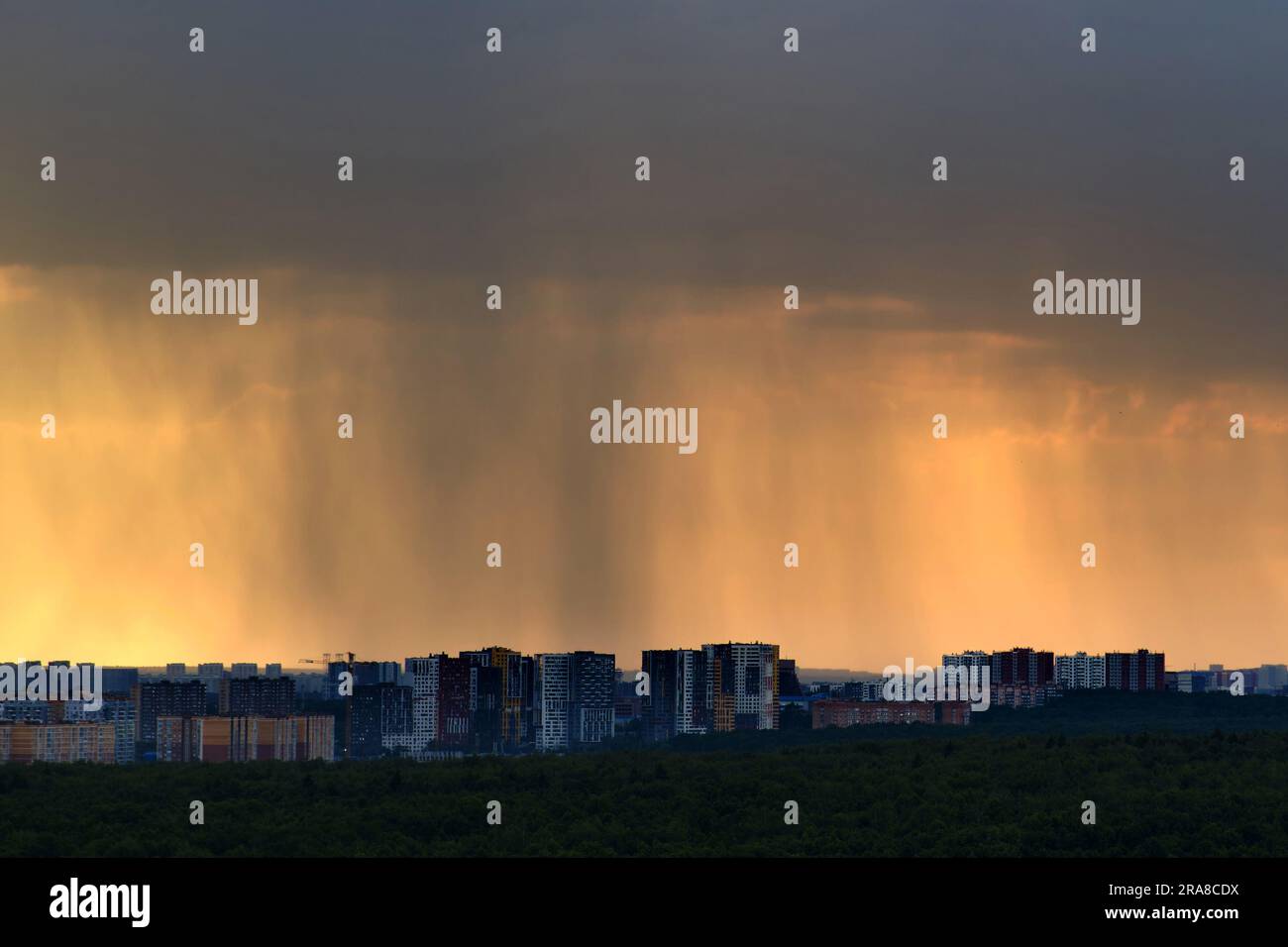 Rain over buildings in the city in the sunset sky. Thunderstorm cyclone ...