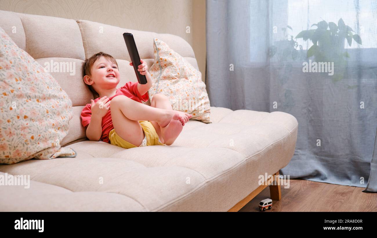 Toddler baby is having fun watching TV while sitting on the high chair ...