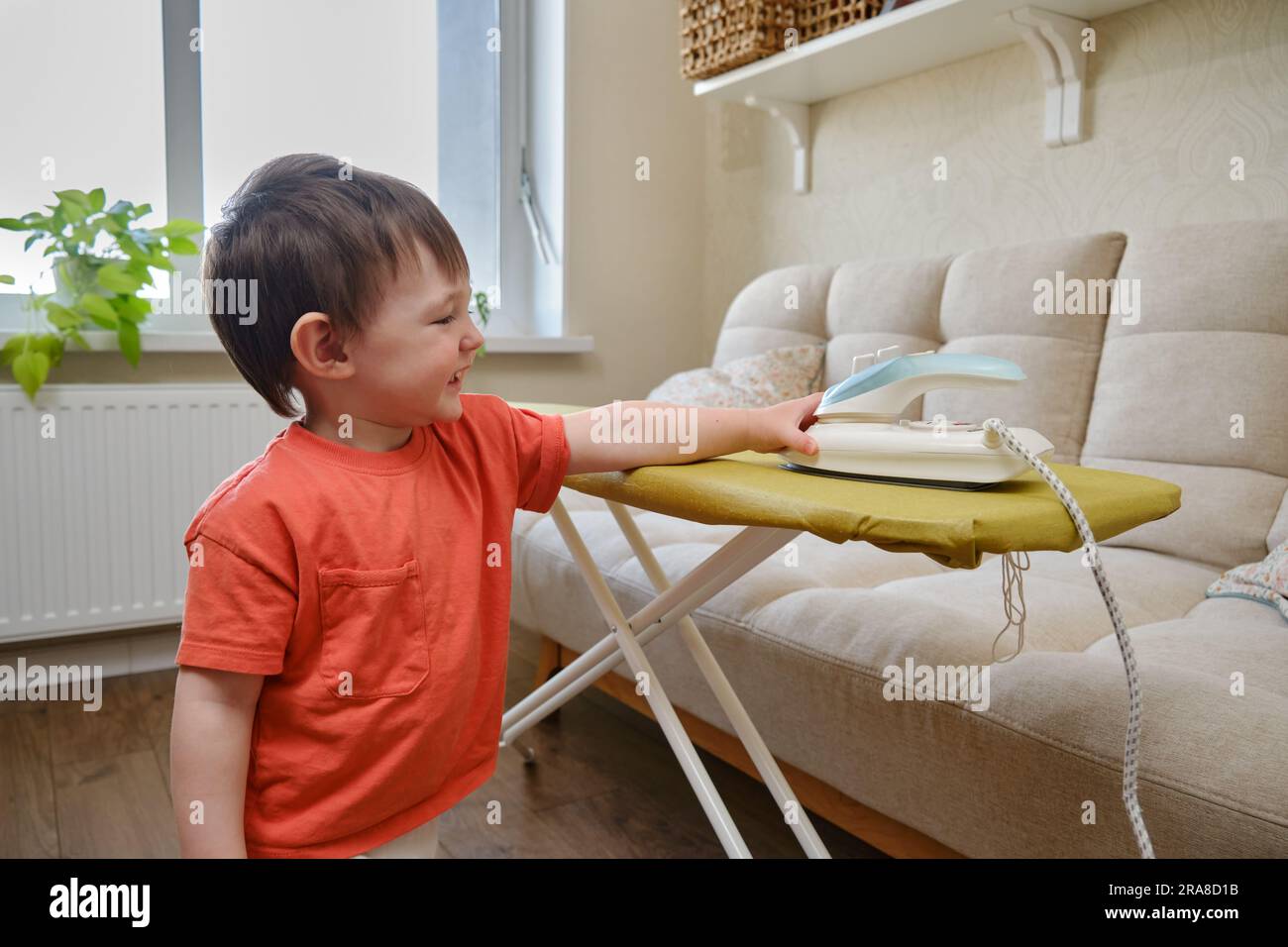 Baby is playing dangerously with a hot iron in the living room of the ...