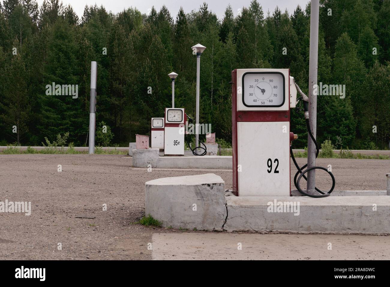 An old suburban gas station on the background of a green forest. A ...