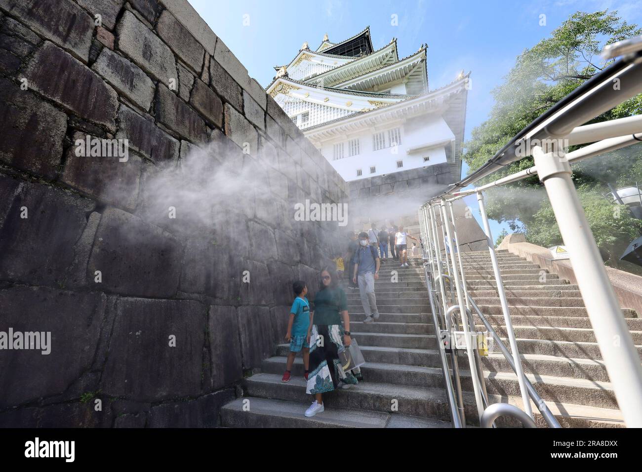 Visitors walk under sprayed mist at Osaka Castle Park in Osaka on July ...
