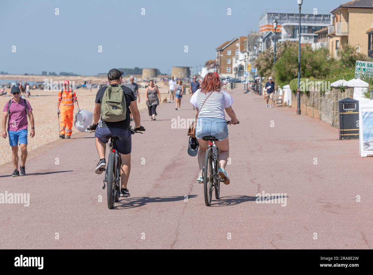 Two cyclists riding bikes along a busy seaside promenade Stock Photo ...