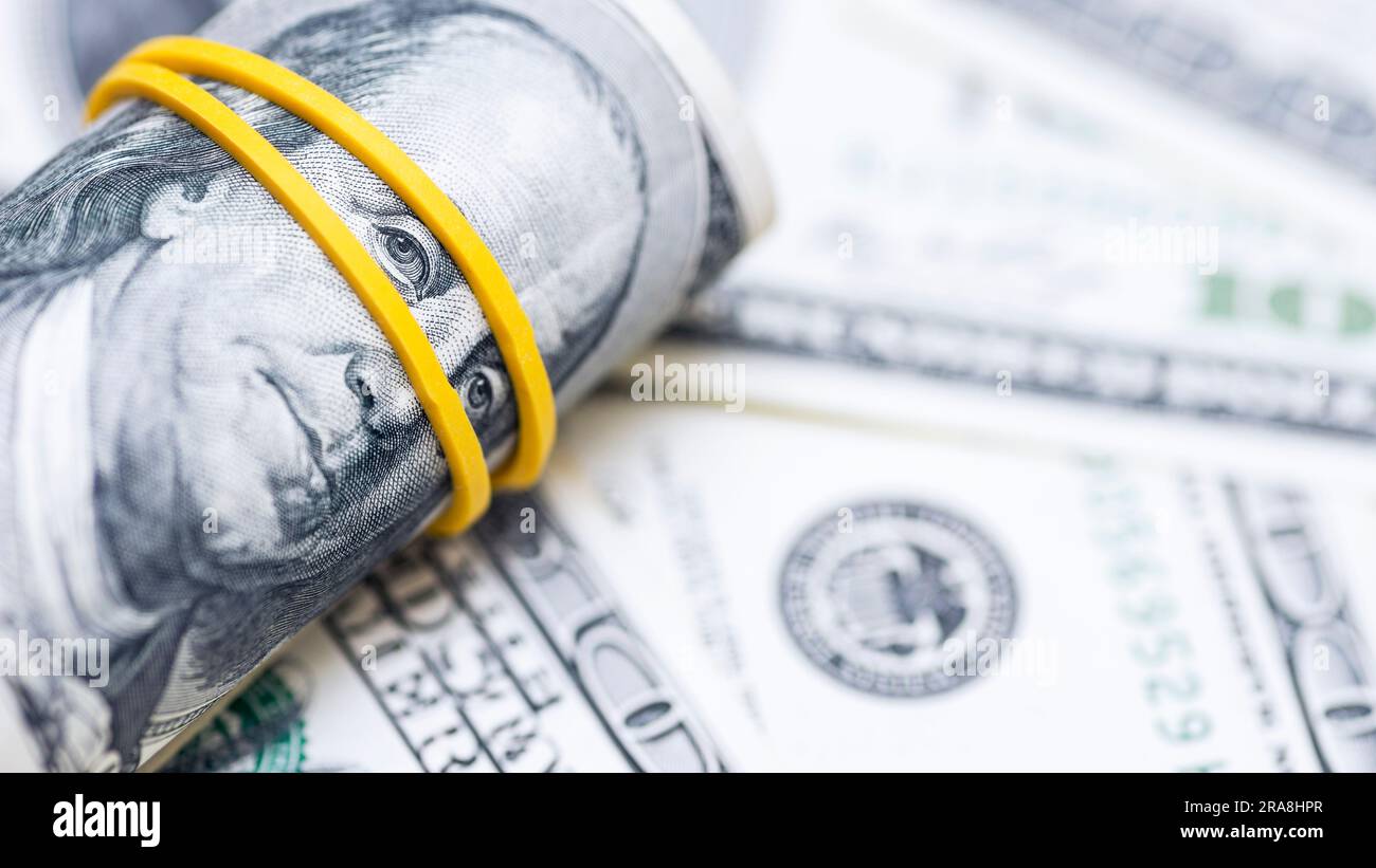 A roll of one hundred dollar bills and tied with an elastic band Stock ...