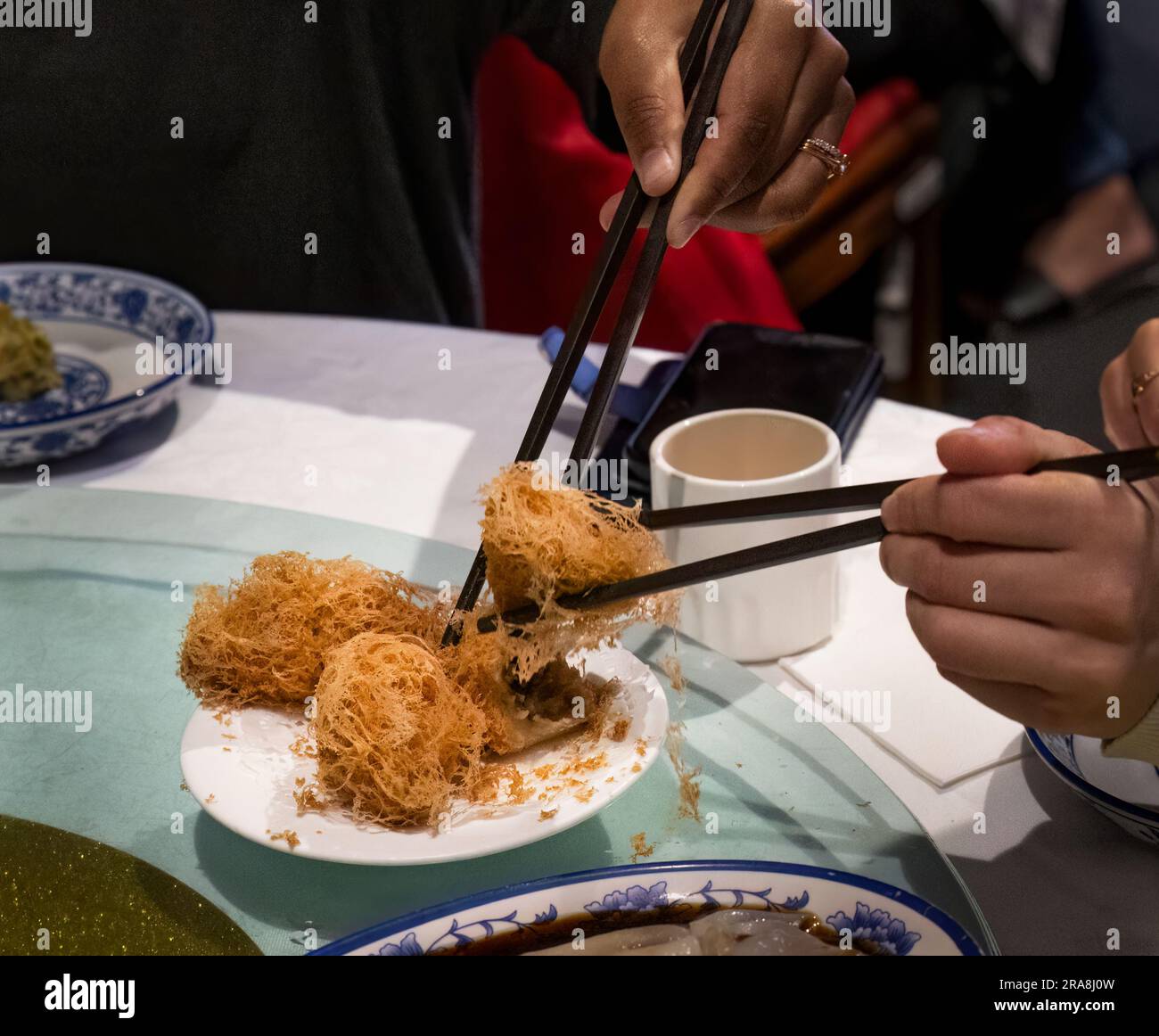 Left-handed women’s hands holding chopsticks and picking Yumcha dishes ...