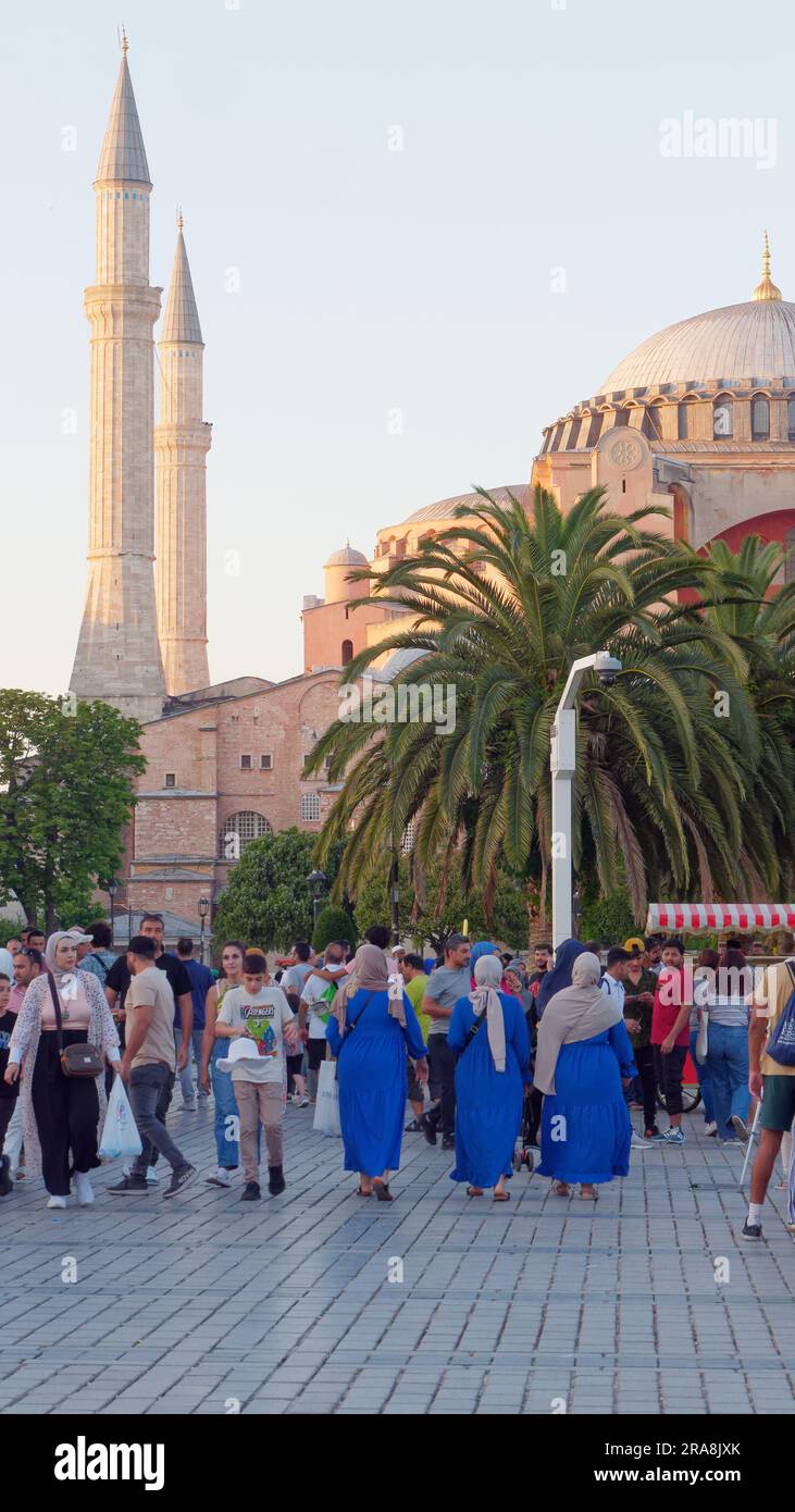 Three muslim women in blue clothes amongst the crowds walk towards the ...