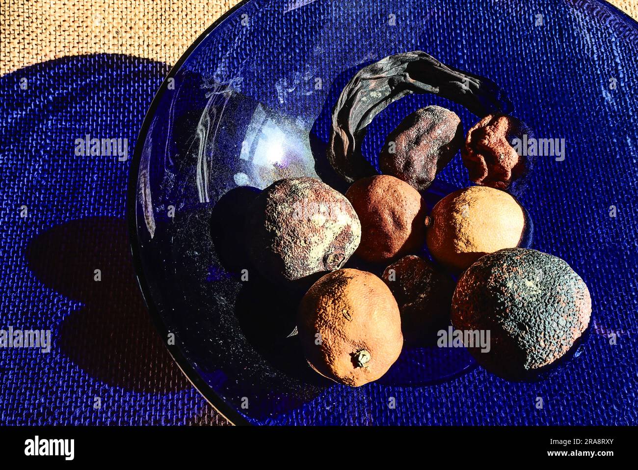 Photo illustration of a blue glass bowl of rotten fruit with strong ...