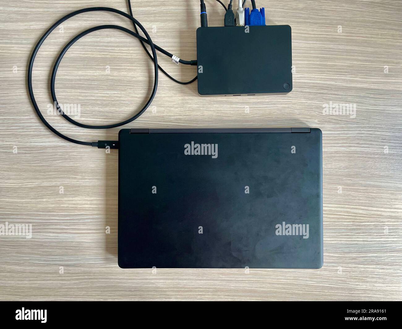 A black laptop connected to a black docking station with a USB cable ...