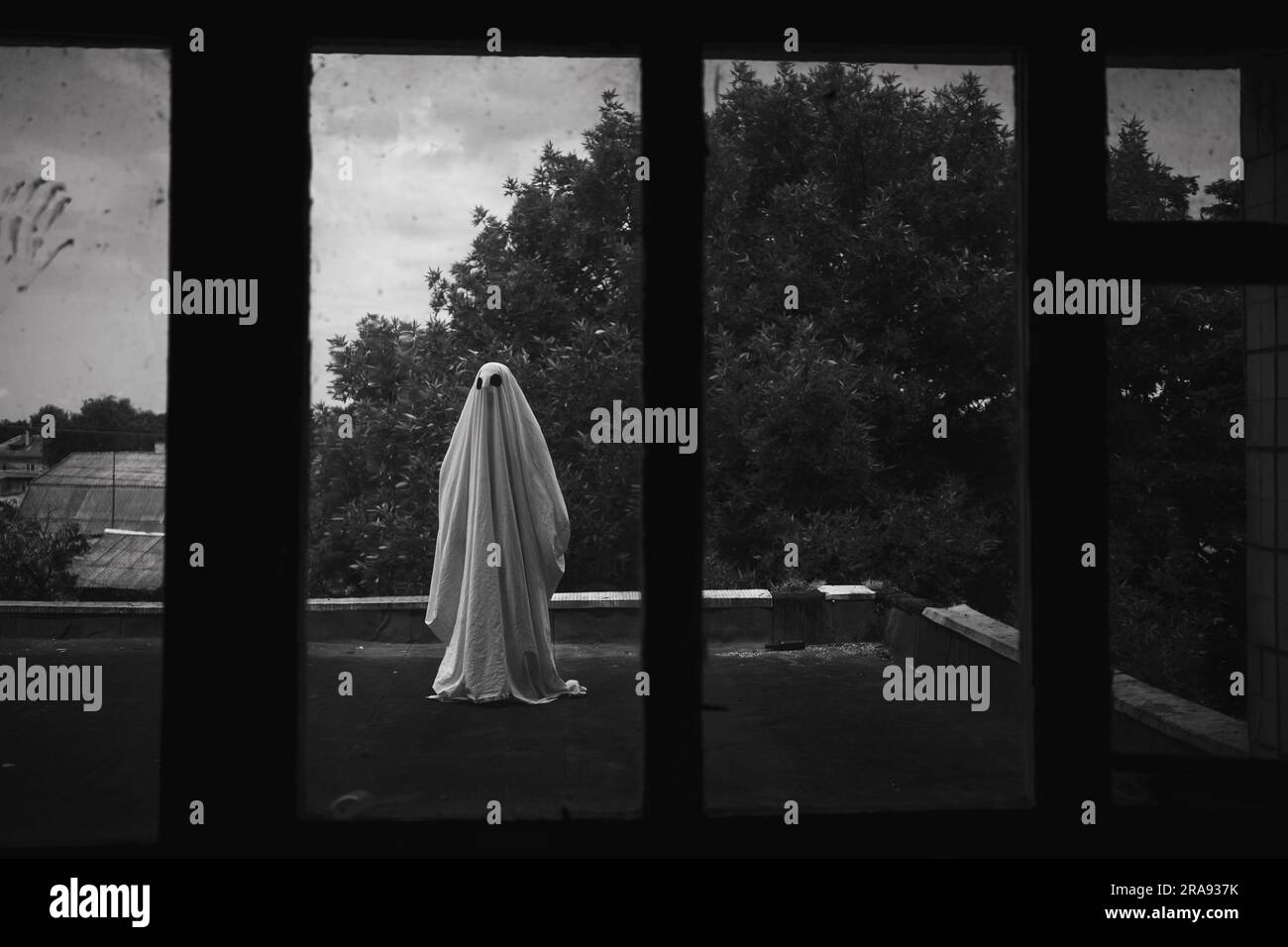 Ghost in a sheet on the roof of an old abandoned house view through the ...