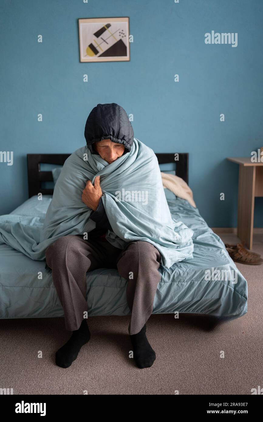 Senior man freezing indoors without central heating. Old male wearing ...