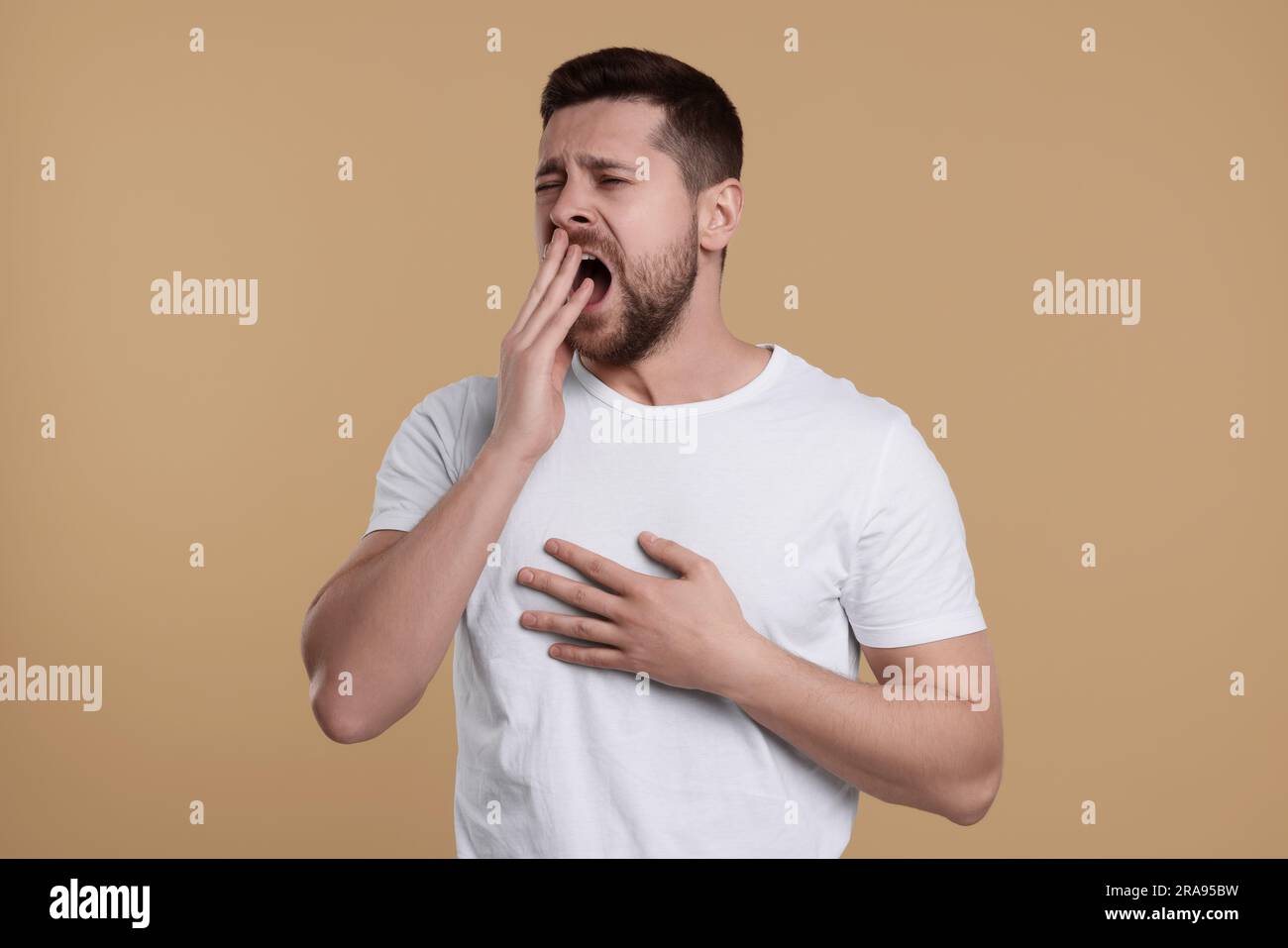 Sleepy man yawning on beige background. Insomnia problem Stock Photo ...