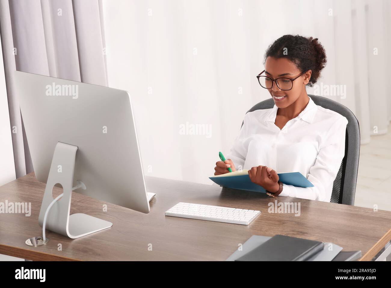 African American intern working with computer at table in office Stock ...