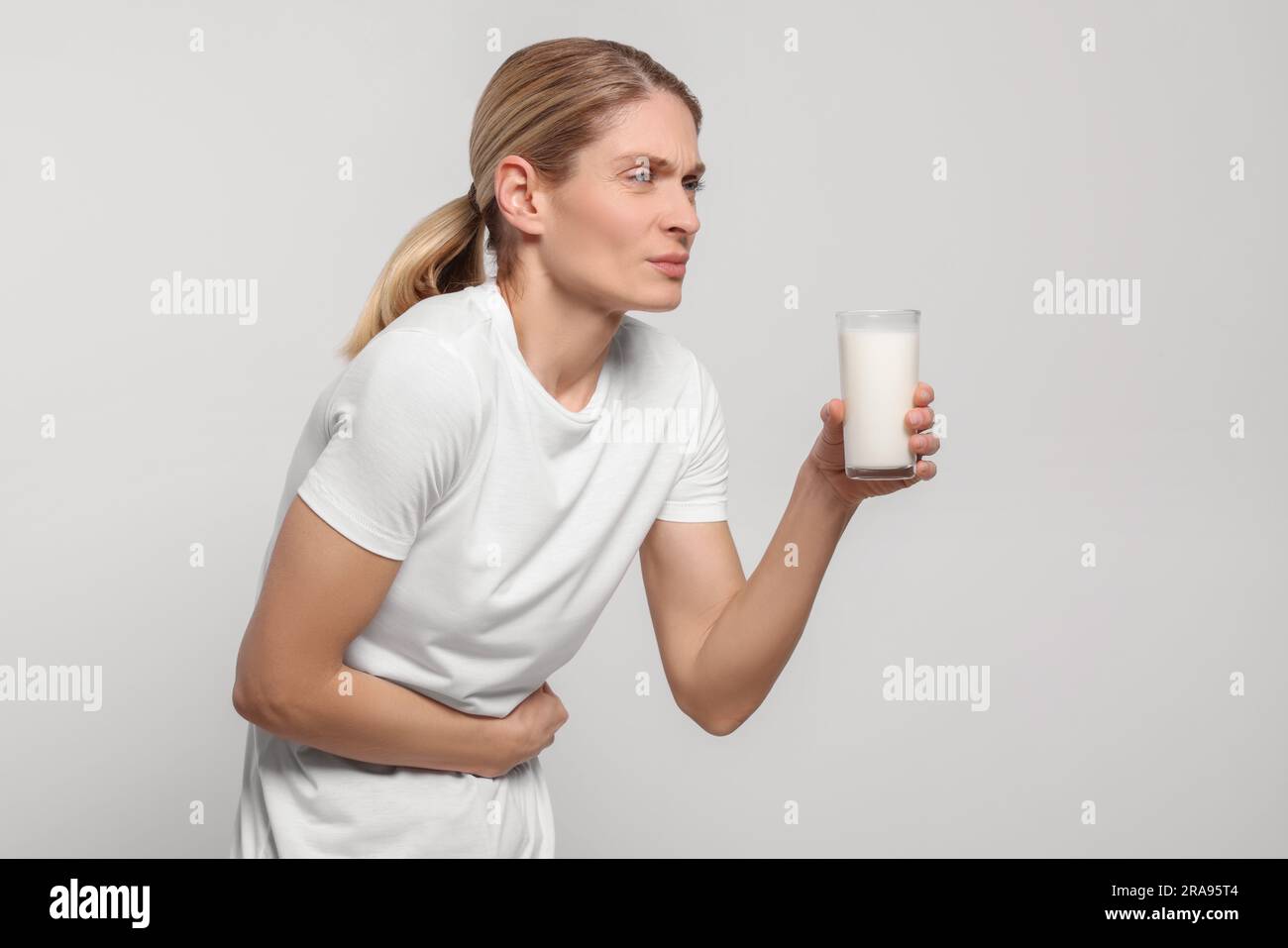 Woman with glass of milk suffering from lactose intolerance on white ...