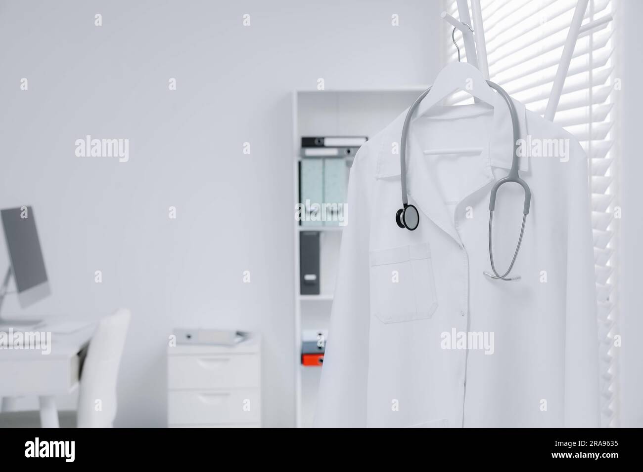 White doctor's gown and stethoscope hanging on rack in clinic. Space ...