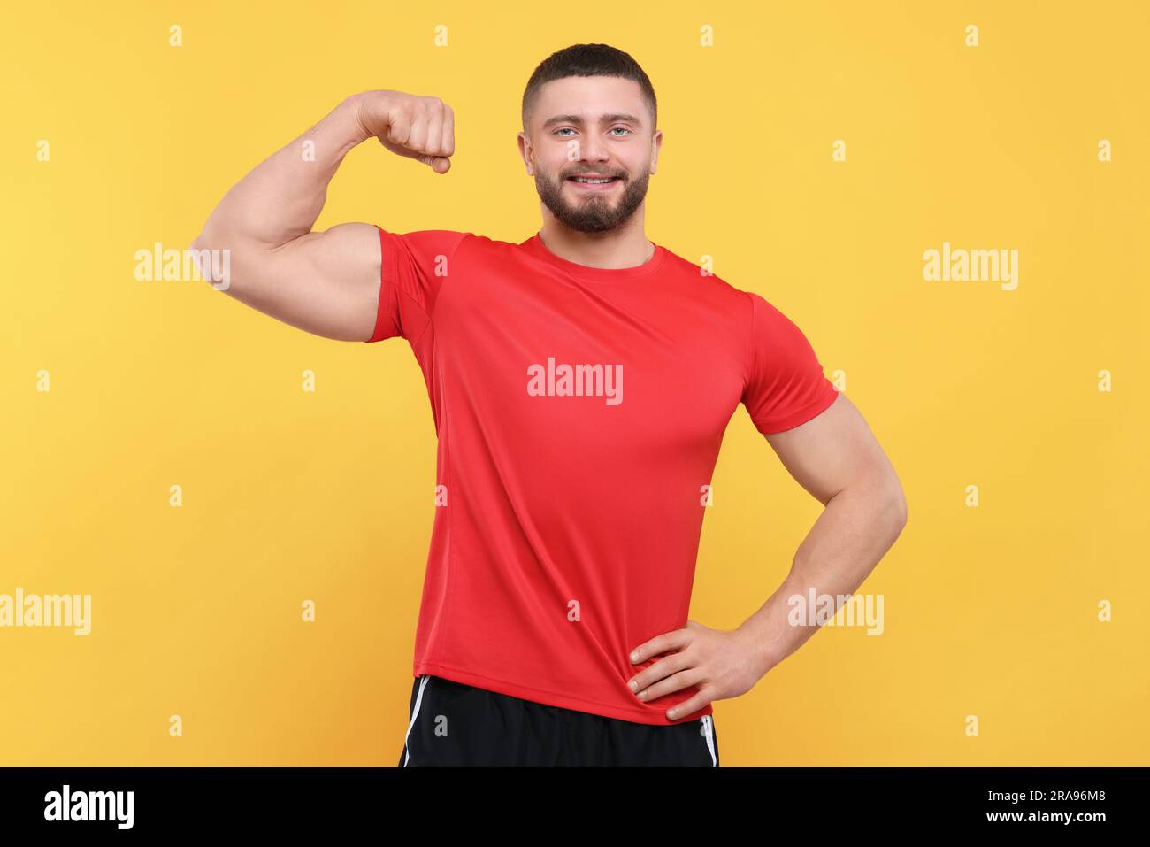 Portrait of handsome man showing muscles on yellow background Stock ...
