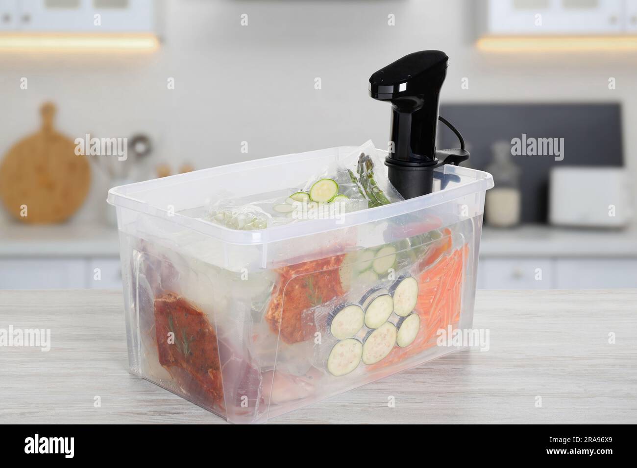 Sous vide cooker and vacuum packed food products in box on wooden table ...