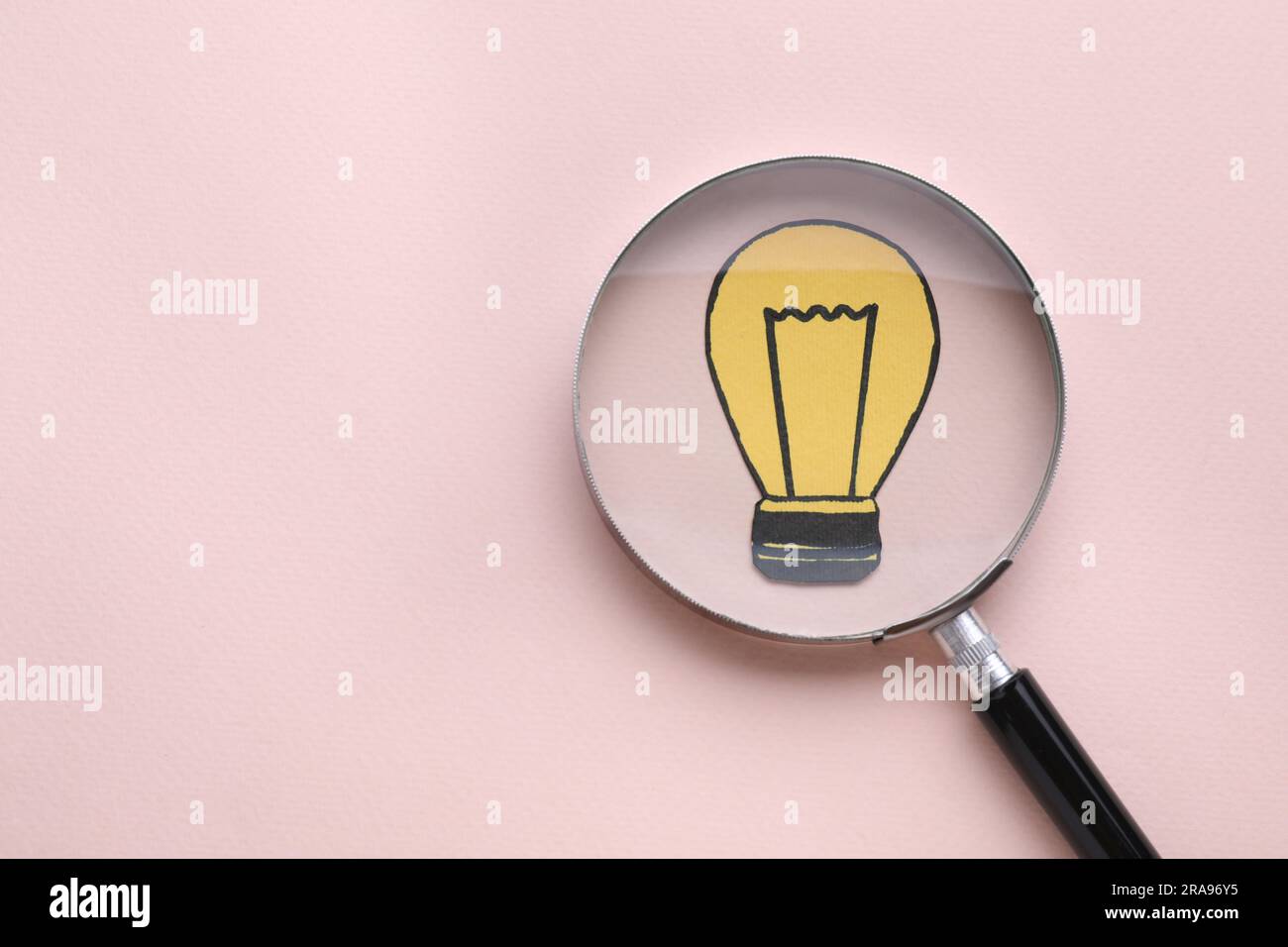 Magnifying glass over paper light bulb on pink background, top view ...