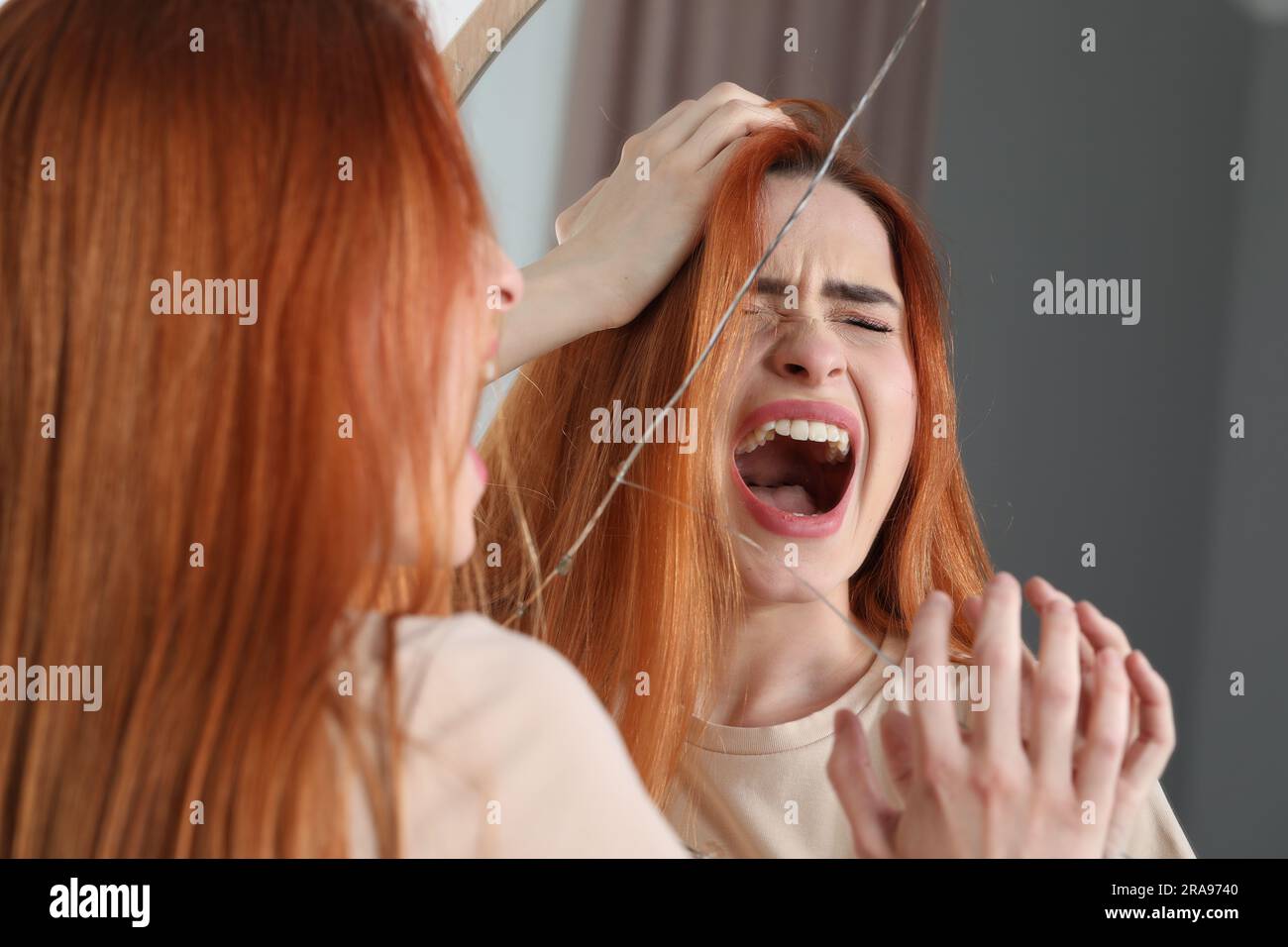 Mental problems. Young woman screaming near broken mirror indoors Stock ...