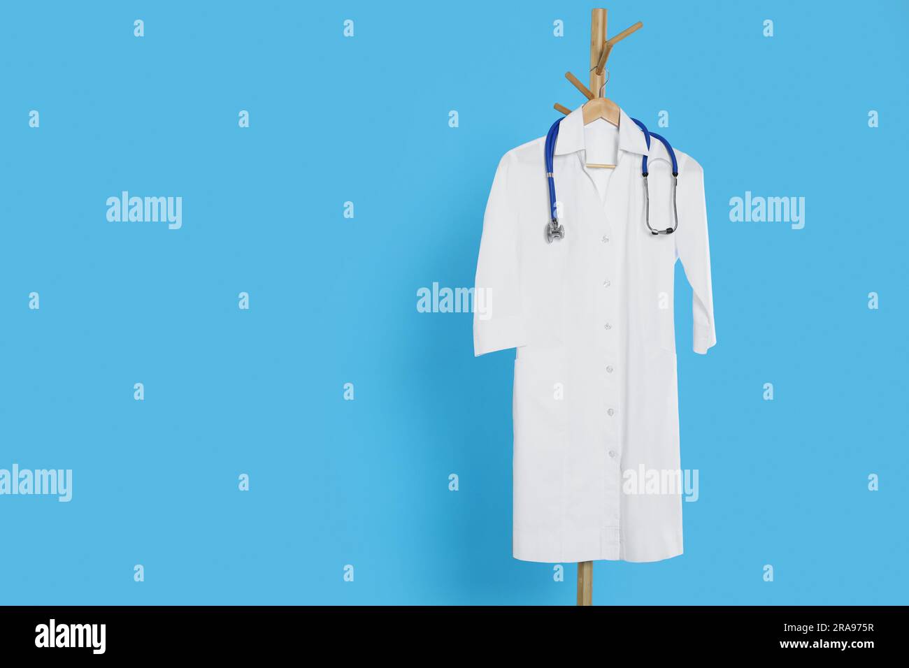 White medical uniform and stethoscope hanging on rack against light ...