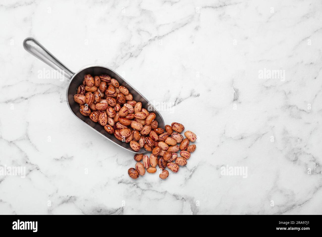 Metal scoop with dry kidney beans on white marble table, flat lay ...