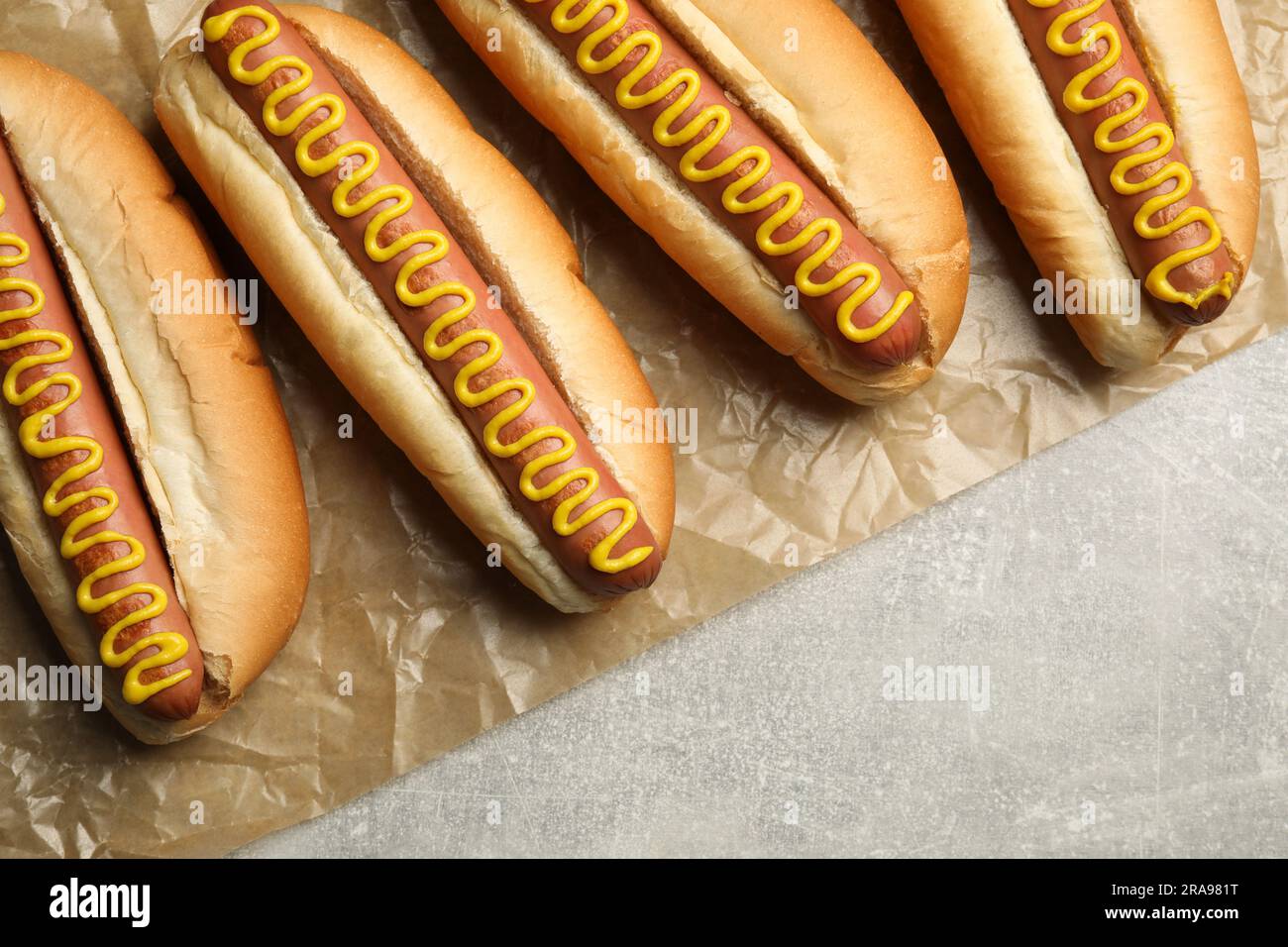 Fresh delicious hot dogs with mustard on light grey table, top view ...