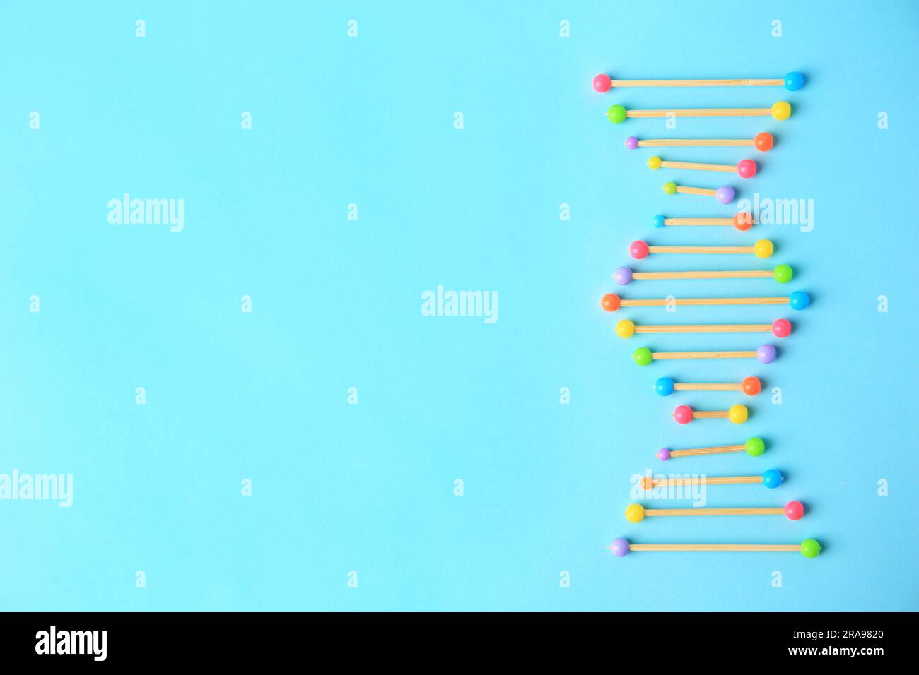 DNA molecule model made of toothpick and colorful beads on light blue ...