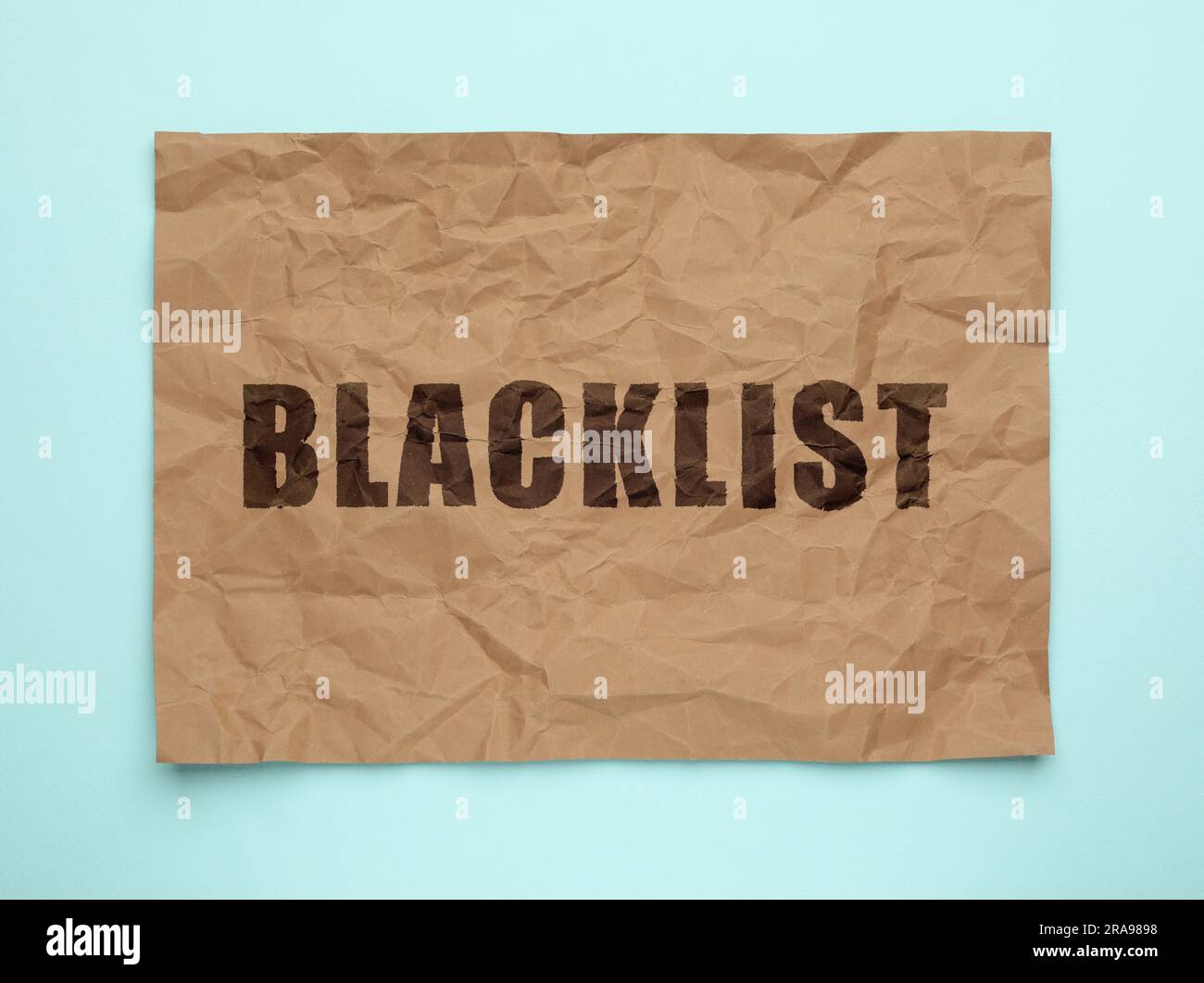 Crumpled paper with word Blacklist on light blue background, top view ...