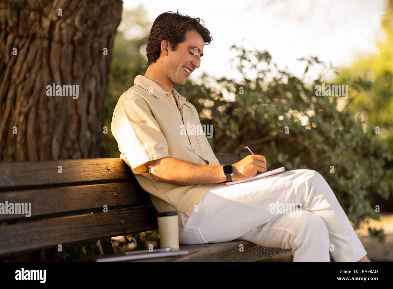 Young man sitting on bench writing on notepad hi-res stock photography ...